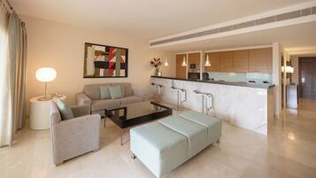 Uma sala de estar moderna com um sofá, uma mesa de centro e um espaço de jantar com cozinha ao fundo.