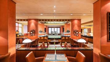 Restaurante com bar central, várias áreas de estar e cardápio à vista.