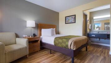 Quarto de hotel com cama, cadeira, mesa de cabeceira, luminária, espelho e mapa fixado na parede.
