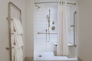 Um chuveiro com entrada direta, porta de vidro, porta-toalhas e um chuveiro.