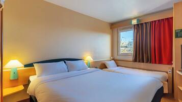 Quarto de hotel com duas camas, janela com cortinas e vista para a cidade.