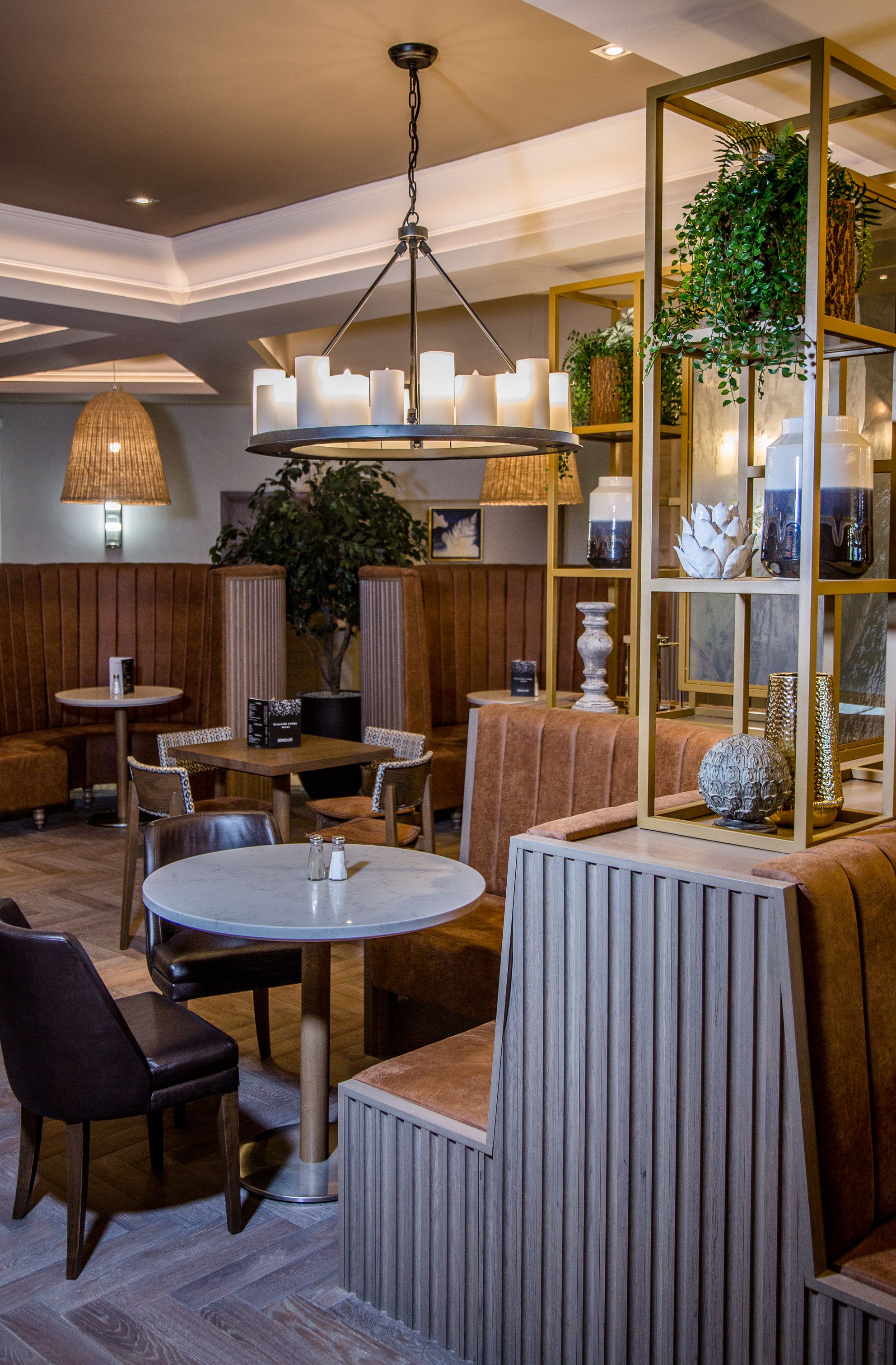 Um restaurante acolhedor com assentos em cabines de madeira, mesas redondas e luminárias pendentes.