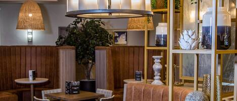 Um restaurante acolhedor com assentos em cabines de madeira, mesas redondas e luminárias pendentes.