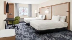 Quarto de hotel com duas camas, uma escrivaninha, uma cadeira, uma televisão e uma janela com cortinas.