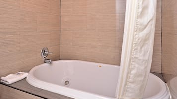 Um banheiro com uma banheira branca, uma toalha e um cortina de chuveiro.