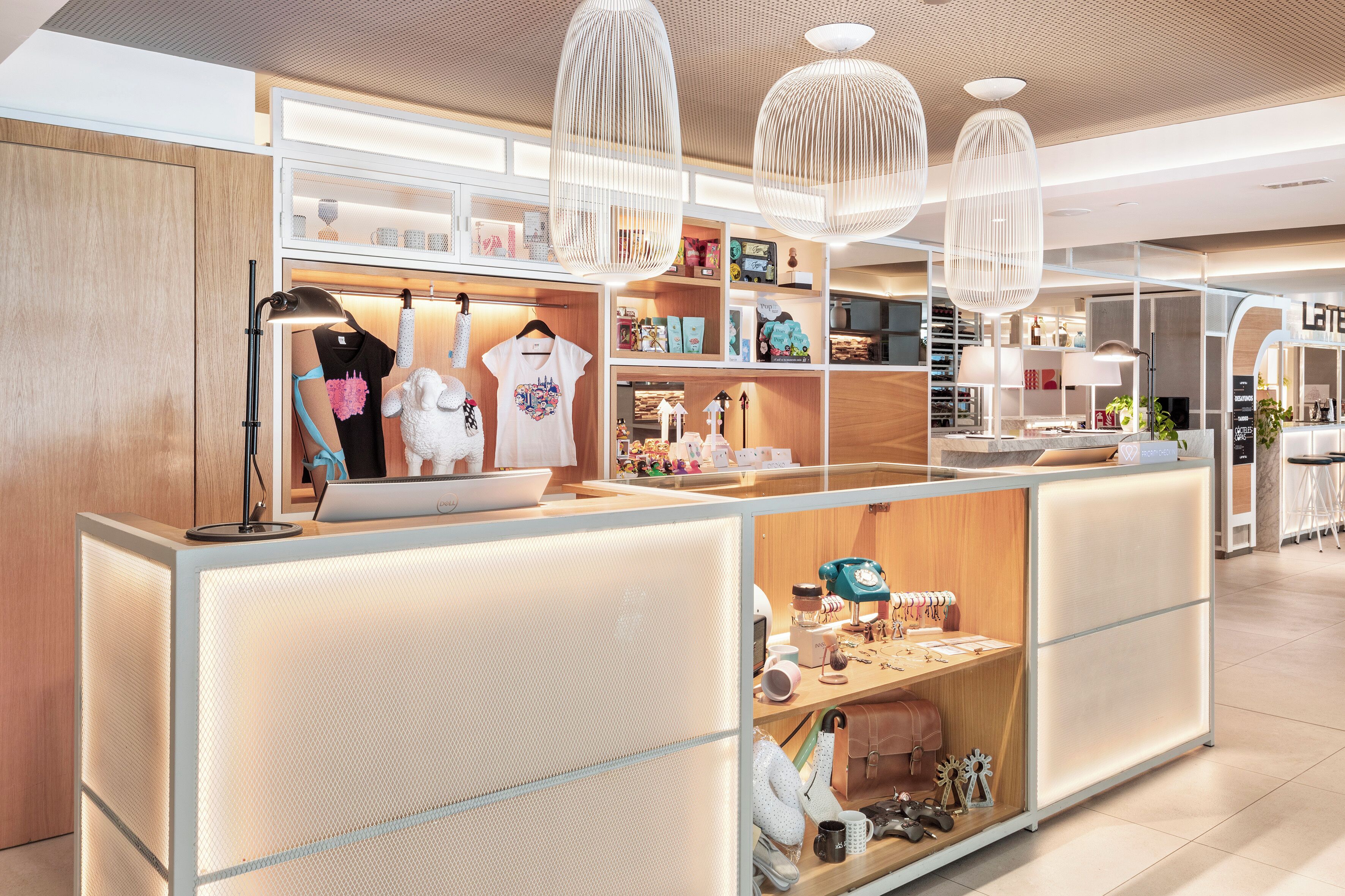 Um espaço comercial moderno com um balcão central, prateleiras com diversos produtos e luminárias pendentes.