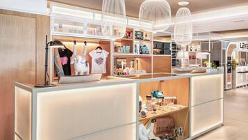 Um espaço comercial moderno com um balcão central, prateleiras com diversos produtos e luminárias pendentes.