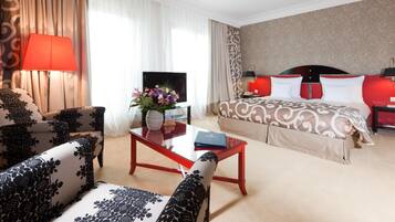 Quarto de hotel com uma cama, duas poltronas, uma mesa de centro, uma televisão e um abajur.