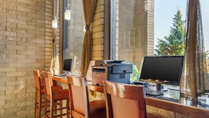 Quarto com parede de tijolos, janela com cortinas, escrivaninha com computador e impressora.