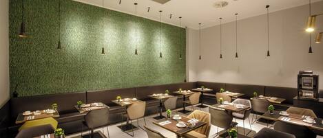Um restaurante moderno com cabines e mesas, paredes texturizadas em verde e iluminação pendente.