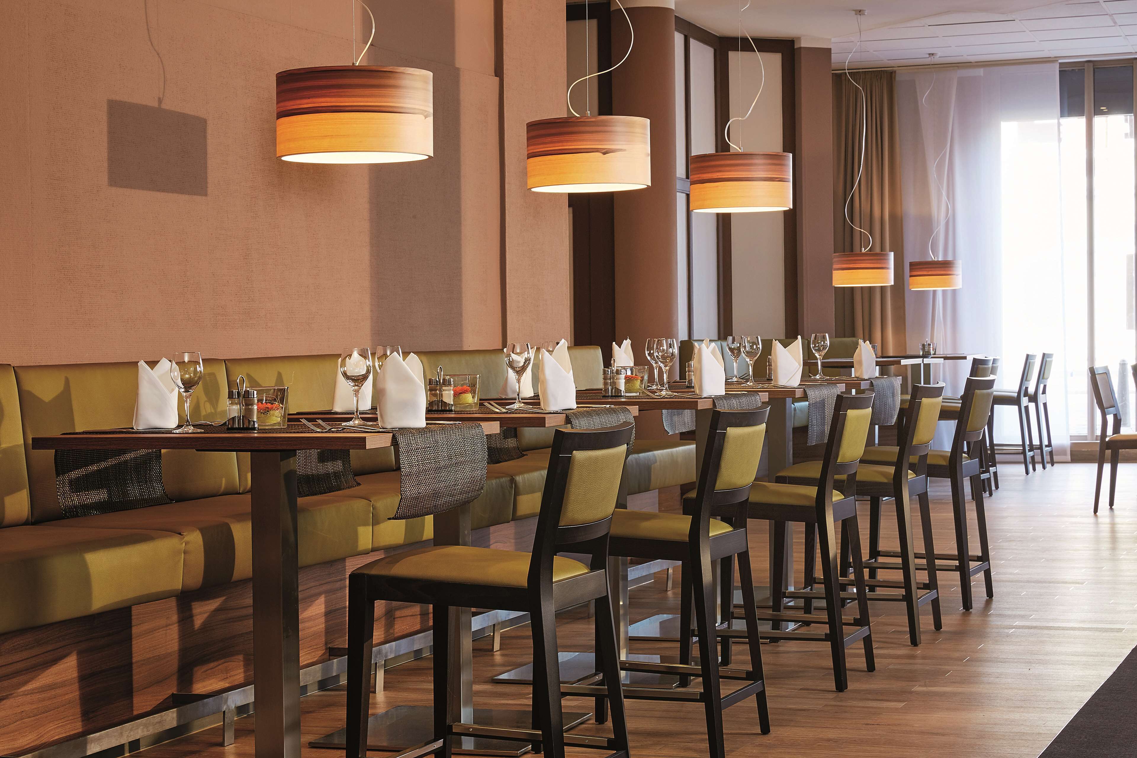 Um restaurante com um balcão comprido, assentos acolchoados e iluminação pendente.