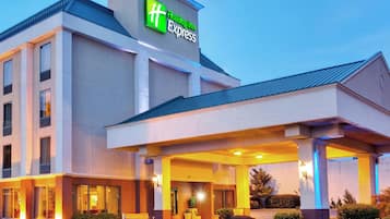 Edifício Holiday Inn Express com entrada coberta e área externa com mesas.