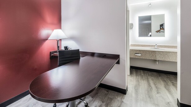 Uma sala de conferências com uma mesa de madeira escura, uma cadeira preta e um abajur branco.