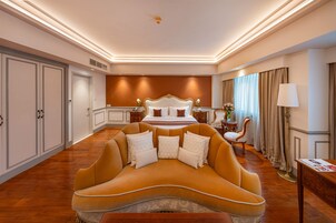 Um quarto espaçoso com uma cama grande, um sofá, uma mesa de cabeceira e um abajur.