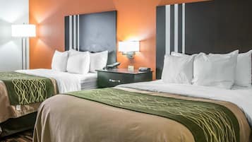 Quarto de hotel com duas camas, cada uma com cabeceira, mesa de cabeceira e luminária, além de telefone.