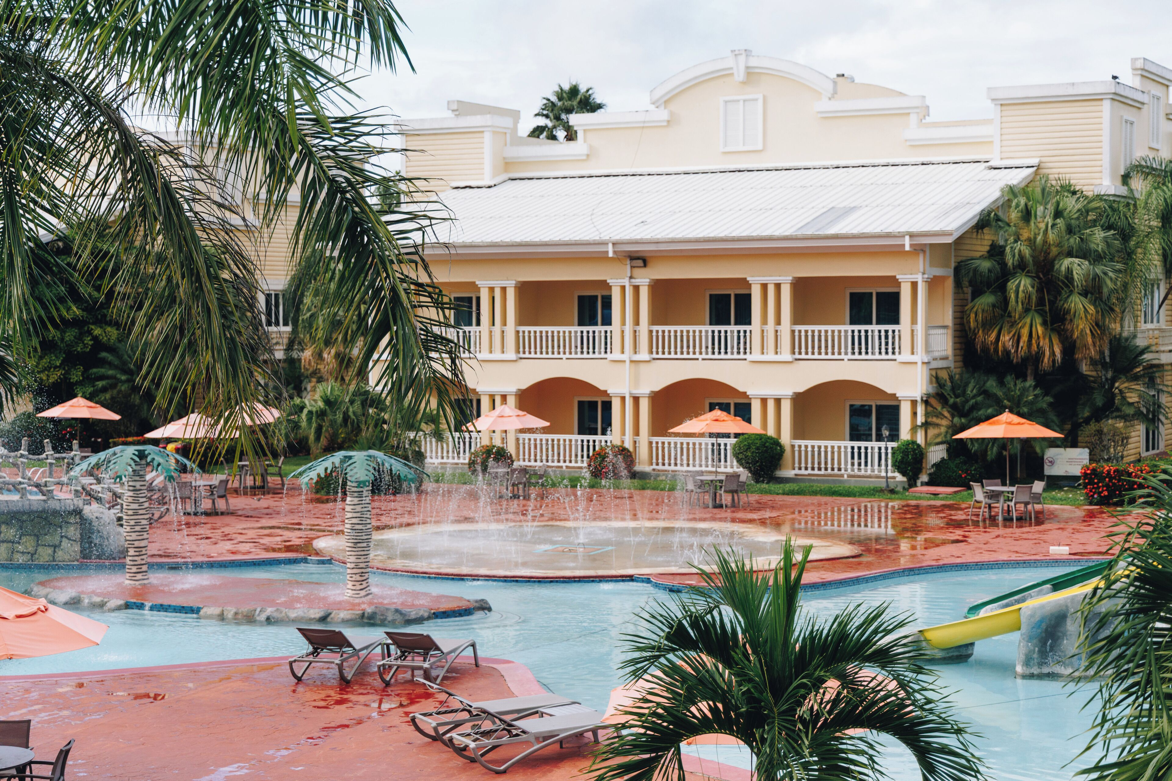 Um hotel com área de piscina, incluindo um elemento aquático, espreguiçadeiras e guarda-sóis.