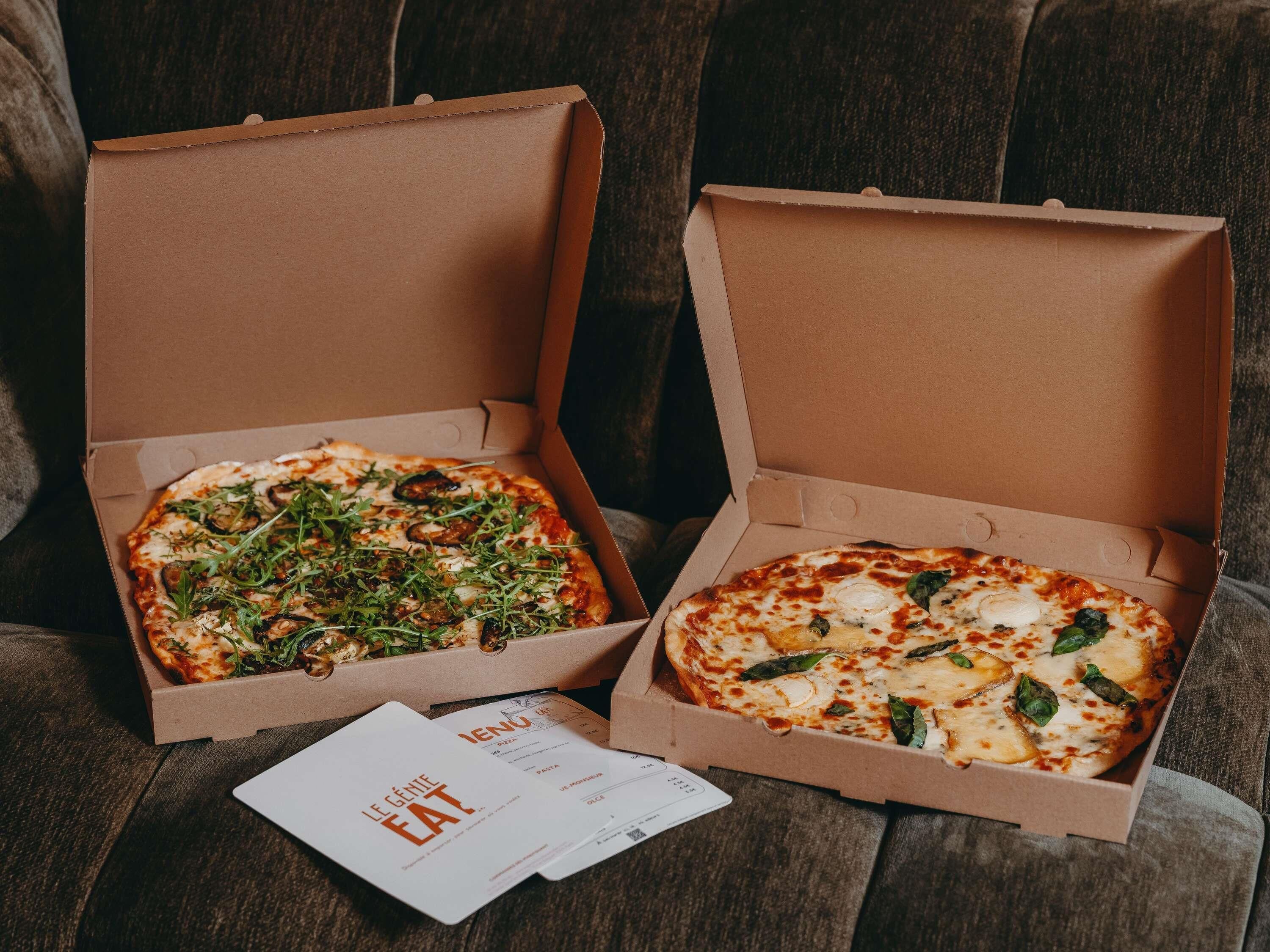 Duas caixas de pizza abertas com cardápios sobre uma superfície de madeira.