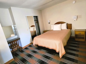 Quarto com cama, mesas de cabeceira, escrivaninha, cadeira, guarda-roupa e espelho.