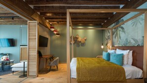 Quarto com cama de dossel de madeira, televisão, escrivaninha e cadeira.