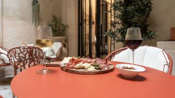 Uma mesa com uma tábua de frios, dois copos de vinho e uma tigela de nozes.