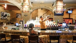 Uma área de bar com arco de pedra, balcão e assentos.