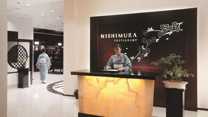 Uma receção com uma placa a indicar "NISHIMURA RESTAURANT" e uma planta em vaso ao lado.