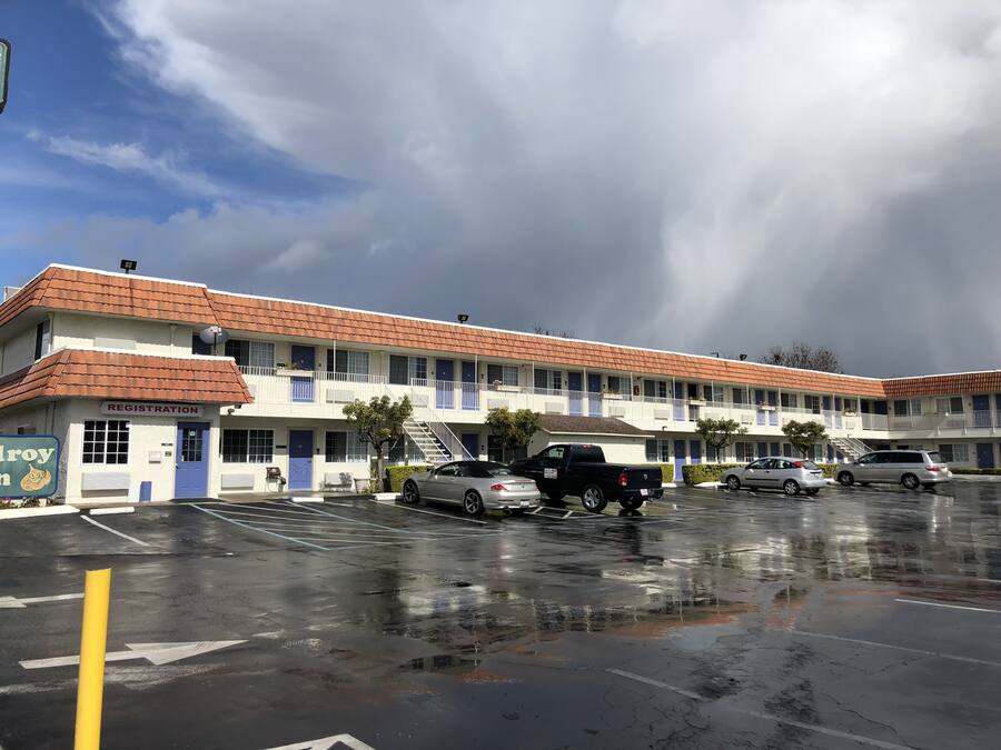 Um motel com uma receção, vários quartos e estacionamento.