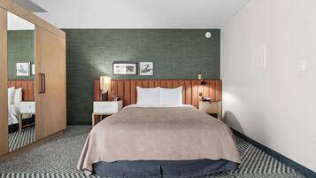 Quarto de hotel com cama, mesas de cabeceira, um espelho e uma parede verde.