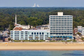 Hotel à beira-mar com um edifício moderno e uma igreja ao fundo.
