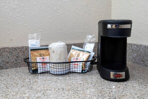 Uma cafeteira e um cesto com saquinhos de chá numa bancada.