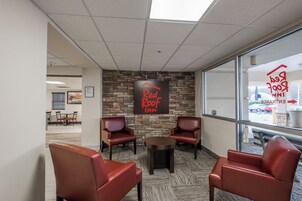 Lobby do Red Roof Inn com parede de pedra, poltronas de couro e uma pequena mesa.