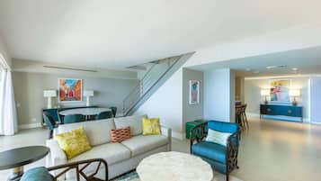 Uma sala de estar moderna com sofá, poltronas, mesa de centro e canto de jantar com cadeiras e mesa.