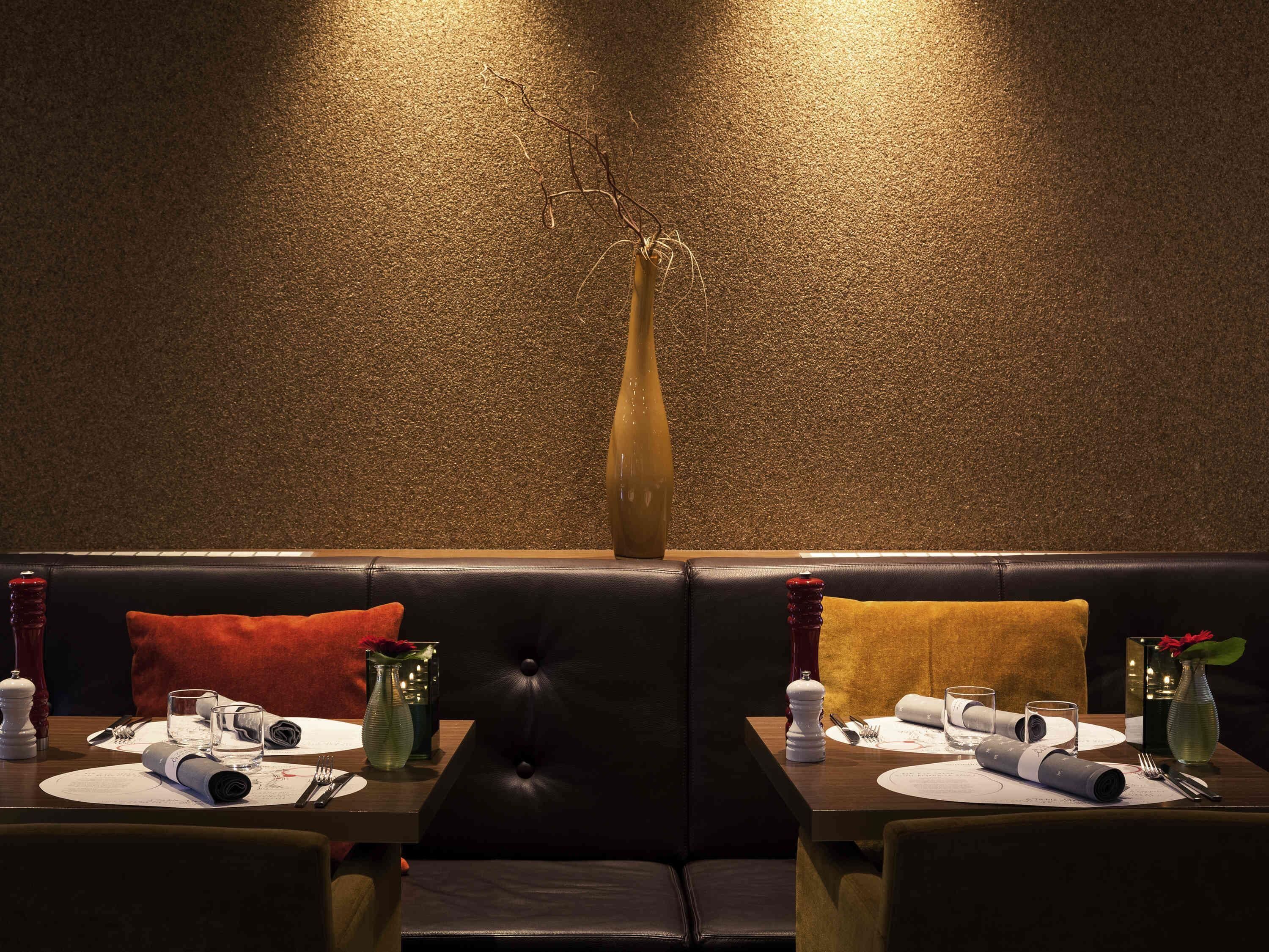 Um restaurante com disposição em cabines, parede texturizada e um arranjo floral no centro da mesa.
