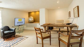 Uma sala de estar moderna com uma mesa de jantar de madeira, poltrona de couro e uma TV exibindo um logotipo.