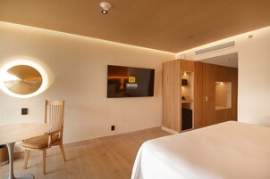 Quarto de hotel moderno com uma cama, uma mesa e uma cadeira.