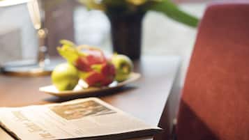 Um close-up de um jornal sobre uma mesa, com um prato de frutas ao fundo.