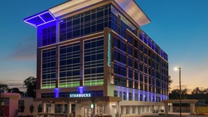 Um edifício moderno com uma Starbucks no andar térreo, com grandes janelas e telhado plano.