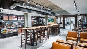 Um restaurante moderno com um balcão comprido, banquetas e um refrigerador expositor.