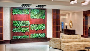 Um hall de entrada com um grande jardim vertical, um sofá e um balcão de recepção.