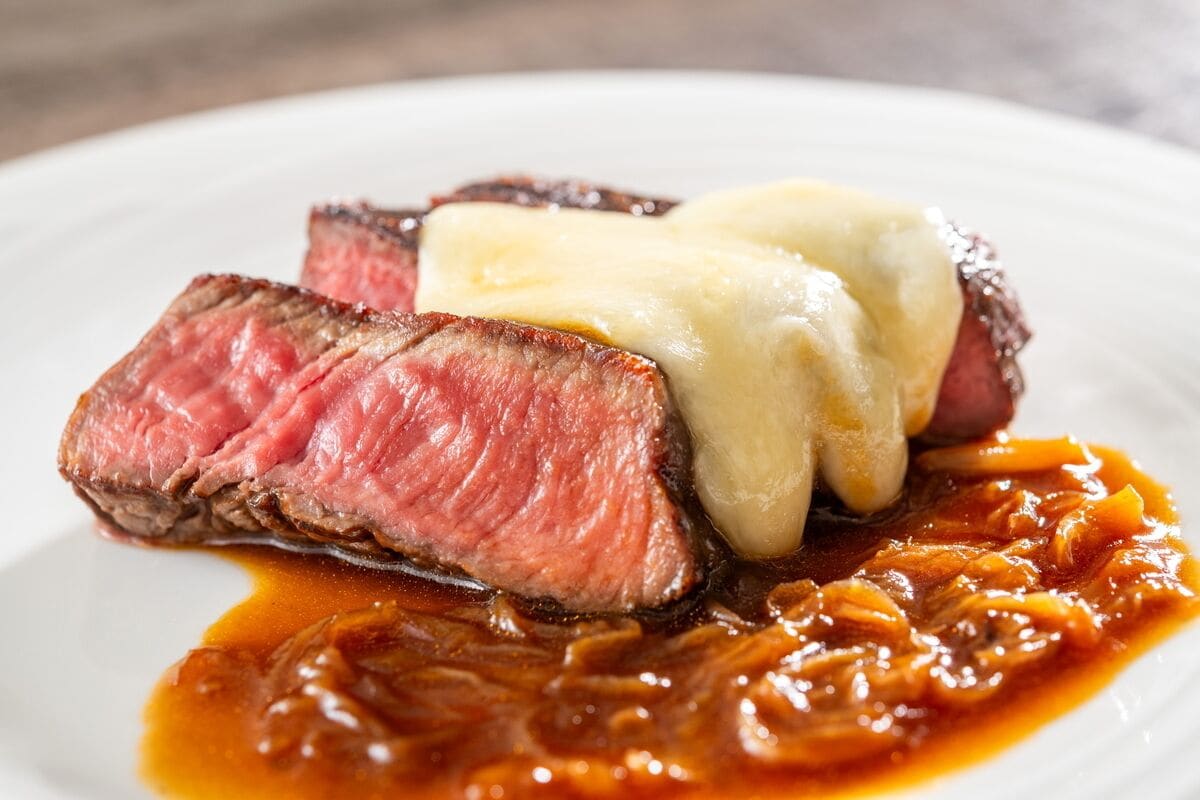 Um prato com bife, purê de batata e molho.