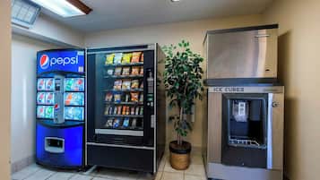 Espaço de máquinas automáticas com refrigerador de Pepsi, diversas opções de snacks e dispensador de gelo.