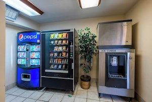 Espaço de máquinas automáticas com refrigerador de Pepsi, diversas opções de snacks e dispensador de gelo.