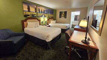 Quarto de hotel com duas camas, uma escrivaninha, uma cadeira e obras de arte nas paredes.
