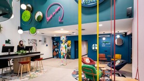 Uma área de recepção de hotel com um letreiro de neon, um balcão de recepção e assentos modernos.