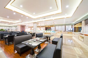 Um restaurante moderno com várias áreas de refeição, incluindo cabines e mesas, e uma cozinha à vista.
