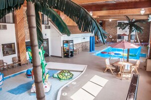 Uma área de lazer interna com piscina, assentos e um mural de uma tartaruga.