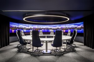 Uma sala de conferências com vista panorâmica da cidade, uma mesa redonda e cadeiras modernas.