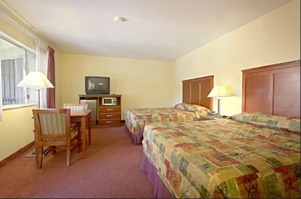 Quarto de hotel com duas camas, uma escrivaninha, televisão e cómoda.