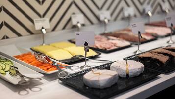 Buffet com diversos alimentos, incluindo queijos, vegetais e carnes.
