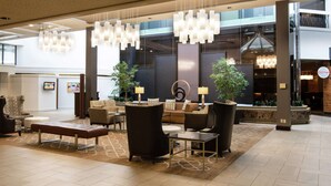 Um hall amplo com móveis modernos, um lustre grande e um letreiro com a palavra 'Gather'.